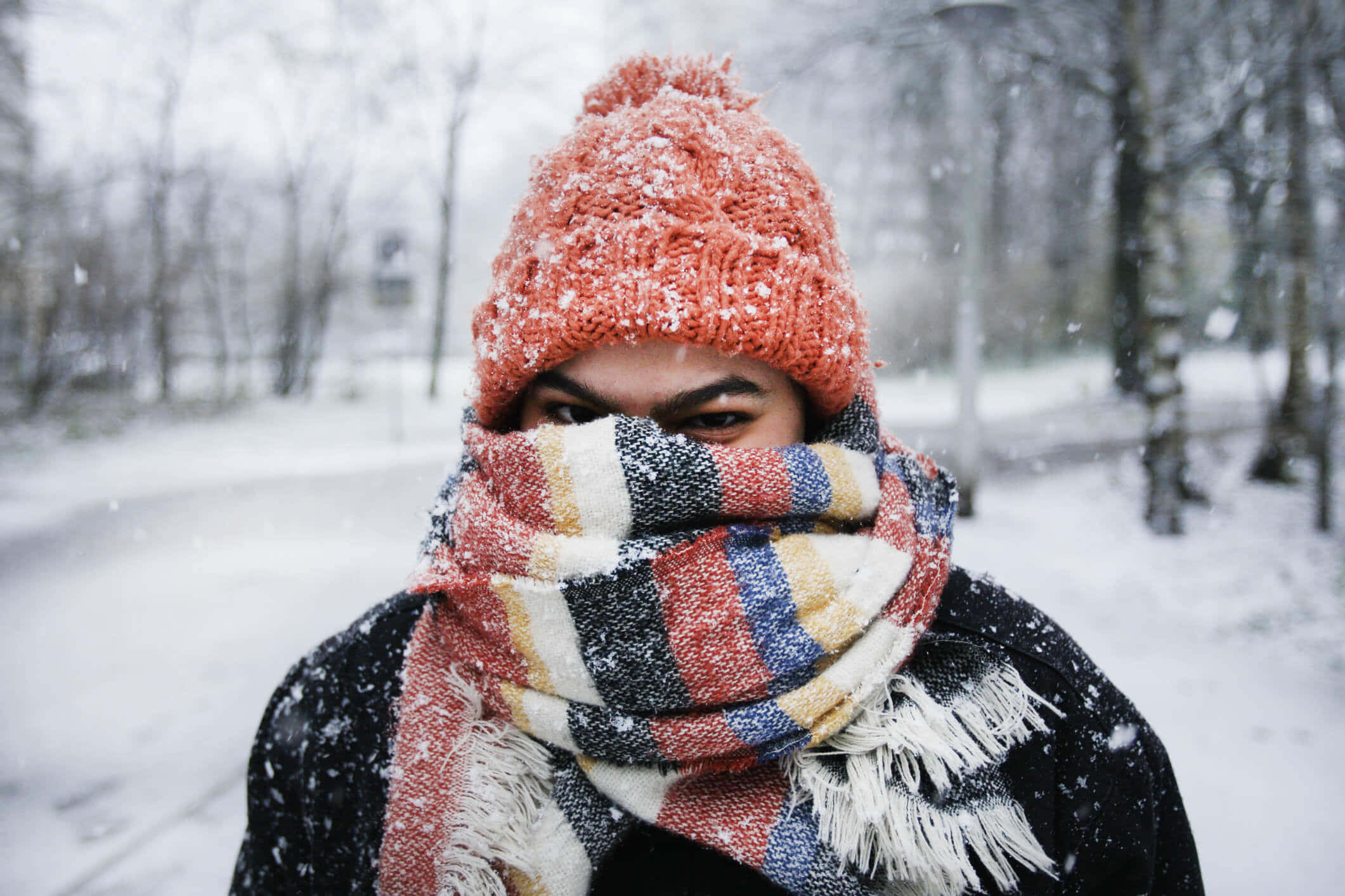 Download A Woman Wearing A Scarf And Hat In The Snow | Wallpapers.com